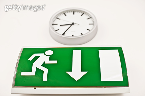 Warning Sign - Emergency Exit Sign Under A Wall Clock (944954284) - 게티이미지뱅크