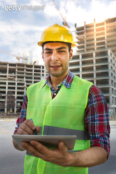 Young Engineer using digital tablet with construction site and crane ...
