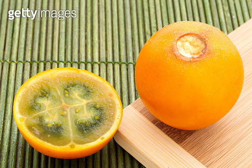 Fruits and slices of lulo or naranjilla on the wooden table - Solanum ...