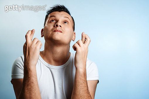 Portrait of a man close-up, crossed fingers, hope, good luck. On a ...