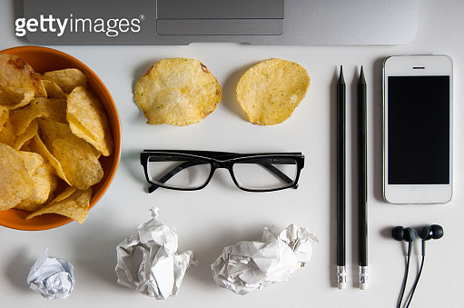 Workspace with laptop,crumpled paper and bowl of chips on wood table ...