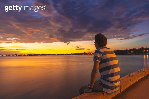Human watching at sunset near water (1062504508) - 게티이미지뱅크