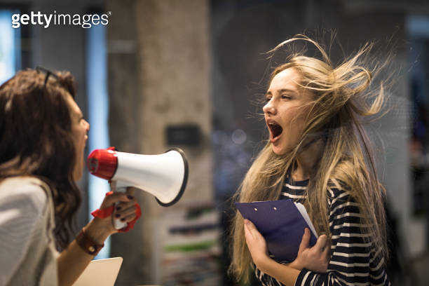Angry female manager yelling at her colleague through megaphone ...