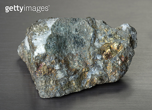 Specimen of mineral chalcopyrite (copper pyrite) on gray background ...
