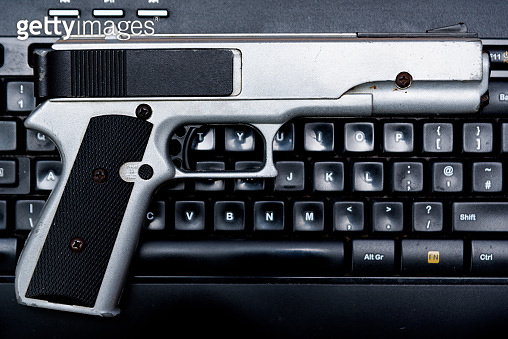 Gun laying on a computer keyboard, (978450432) - 게티이미지뱅크