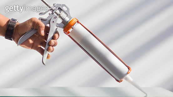 Construction workers installing windows and using silicon, gun with ...