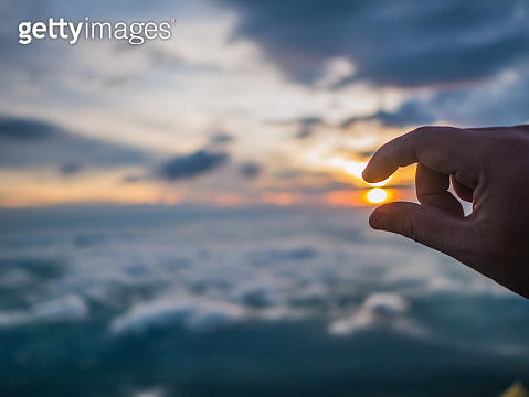 Human Hand trying the pick up the sun on beautiful Sunrise with idyllic ...