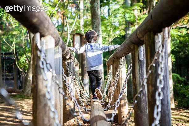 Log bridge type playground equipment in the park. Children are playing ...