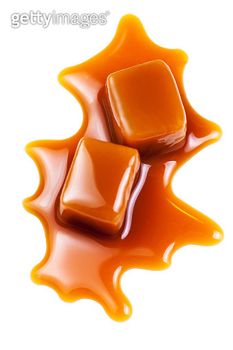 Sweet Caramel sauce flowing on caramel candy isolated on white ...