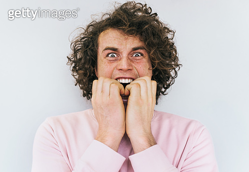 Closeup portrait of young male model with curly hair, with scared and ...