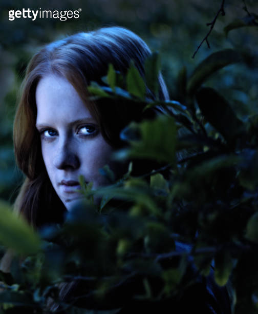 Suspicious young woman peeping through bushes at night 이미지 (1059118392 ...