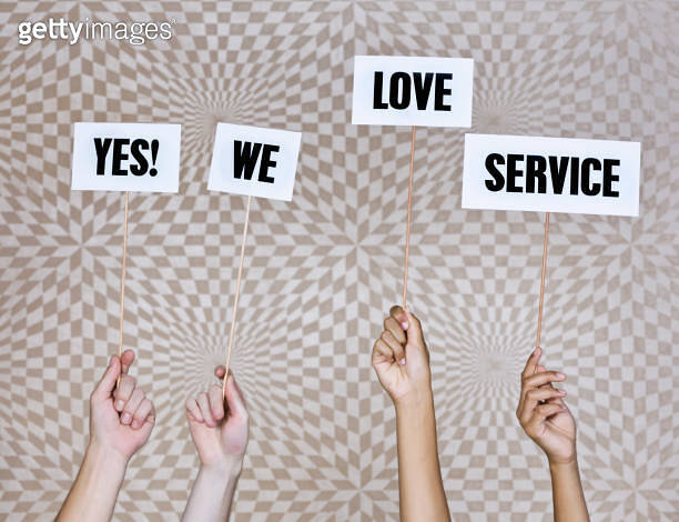 Four hands hold up sign: "Yes! We love service" 이미지 (958713926) - 게티이미지뱅크