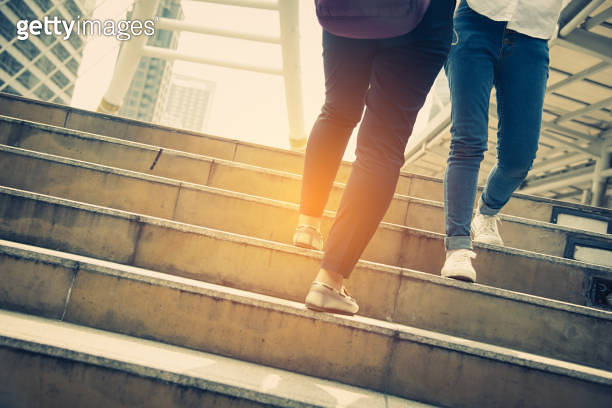 Close up legs of two traveling people walking on stepping up stair in ...