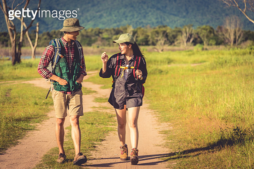 Two people walking on path in meadow field. Male and female traveler ...
