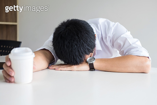 Tired businessman sleeping at work in modern office with hand holding ...