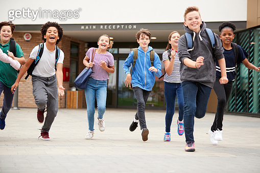 Group Of High School Students Running Out Of School Buildings Towards ...
