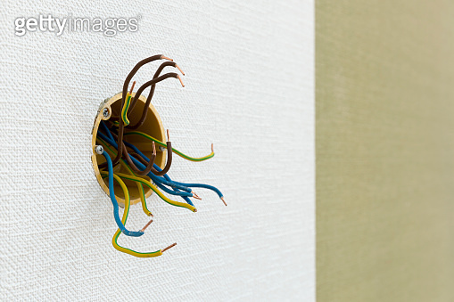 Several exposed electrical copper wires protruding from a whitewall ...
