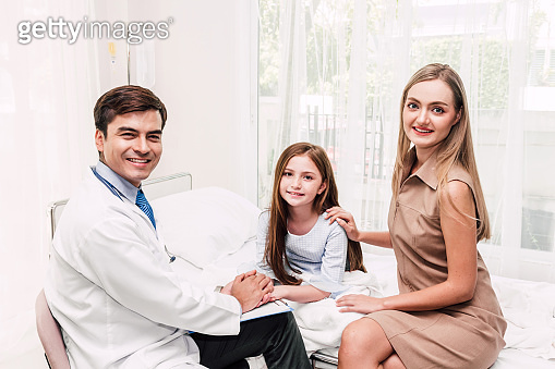Doctor holding hand little girl with care on doctors table in hospital ...