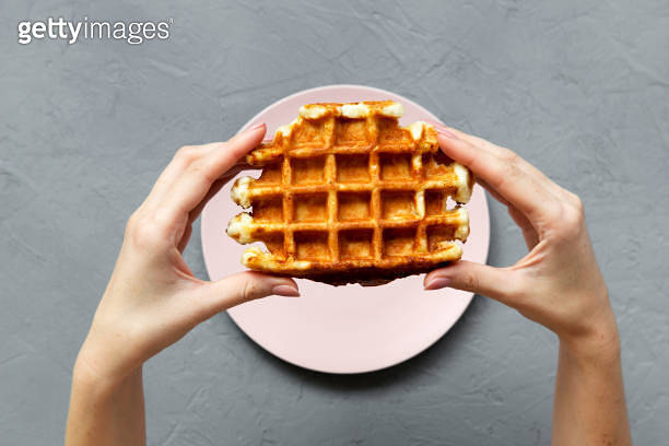Female hands holding traditional belgian waffle over concrete ...