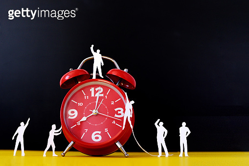 little paper men next to a big clock, an alarm clock. The concept of ...