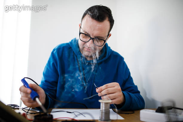Young man soldering a soldering wires together ,work on the table ...