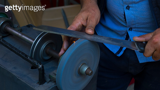 Man grinding on abrasive cutting and knife-sharpening stones ...