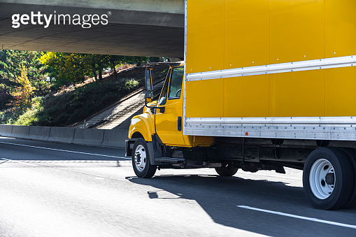 Yellow small rig semi truck with box trailer transporting local ...