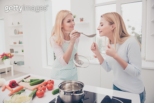 Professional mother in apron giving to try tasty homemade bouillon to ...