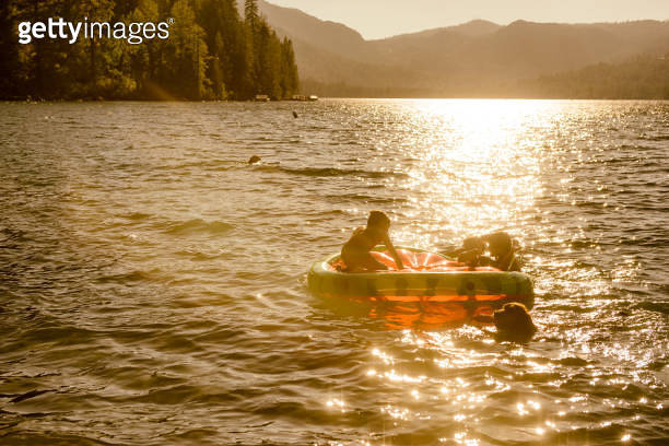 Friends and family playing on an inflatable raft on a beautiful lake at ...