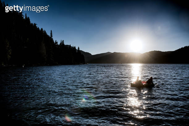 Friends and family playing on an inflatable raft on a beautiful lake at ...