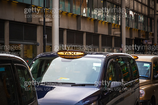 London black cabs lined up on sidewalk waiting for customers outside ...