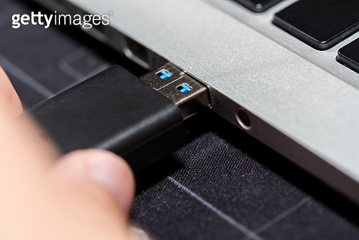 Hand inserting USB flash memory drive plugged into a computer laptop ...