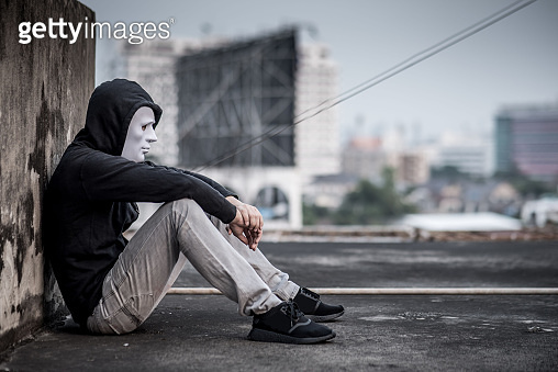 Mystery man in white mask sitting with sad eyes in abandoned building ...