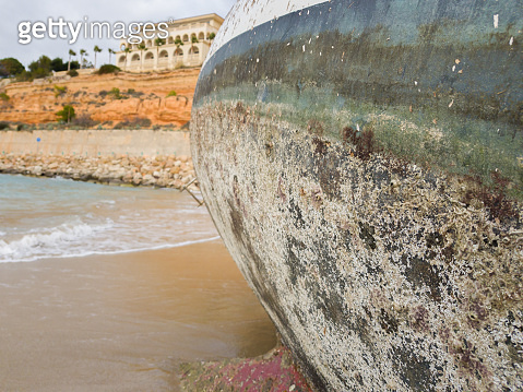 Barnacle growths on the bottom of a sailing boat lying on the shore ...
