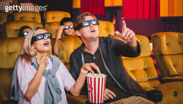 Happy young couple lover watching action movie in theater/theatre ...