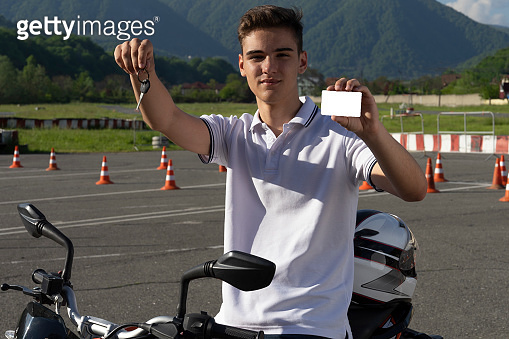 Teen on the scooter is showing driving license and motorcycle key. Copy ...