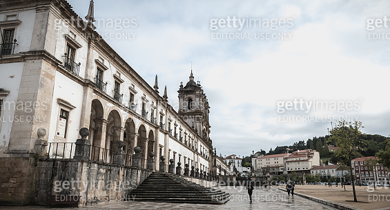 People walk in the rain in front of Alcobaca Monastery, Portugal ...