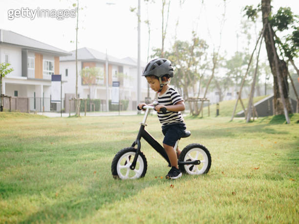 Asian little boy riding his bike with sport helmet outside on a sunny ...
