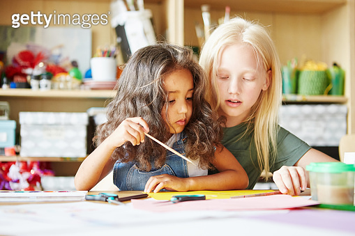 Adorable albino girl helping friend to draw picture while sitting in ...
