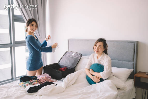 an asian chinese female packing her luggage while her sister sitting on ...