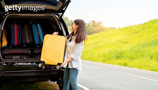 Happy travel of asian woman trucking luggage suitcase to back suv car ...