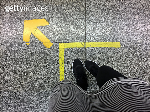 Feet and arrows on road. Yellow sign of arrow direction and standing on ...