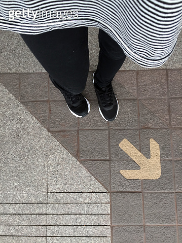 Feet and arrows on road. Yellow sign of arrow direction and standing on ...