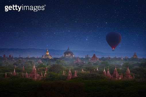 Night landscape of Bagan with overflying balloon over ancient temples ...