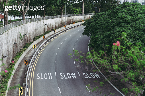 Warning road signs along a bend road indicating the word “Slow ...