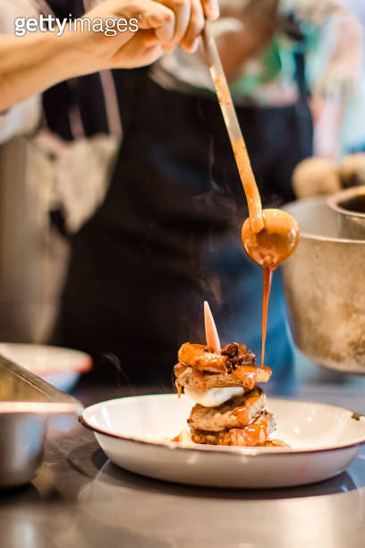 Young Chef Pouring Gravy On Potato Fries and cheese curds. Canadian ...