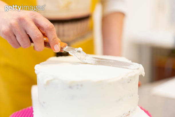 Close up of woman putting icing on the top of a cake 이미지 (1154476989 ...