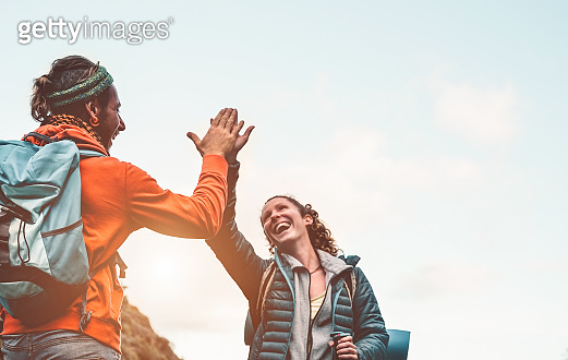 Happy friends stacking hands while doing trekking excursion on mountain ...