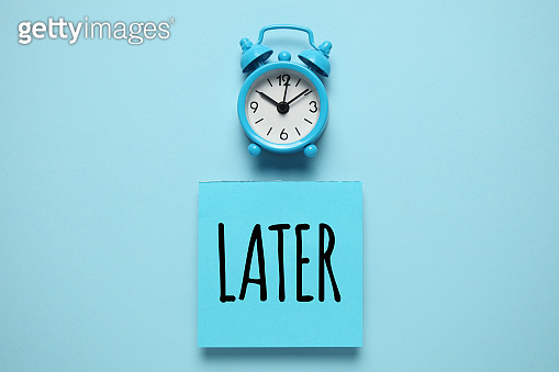 Blue alarm clock and paper reminder, later. Time management, priorities ...