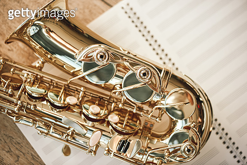 The joy of sax. Top view of beautiful shiny saxophone lying on sheets ...
